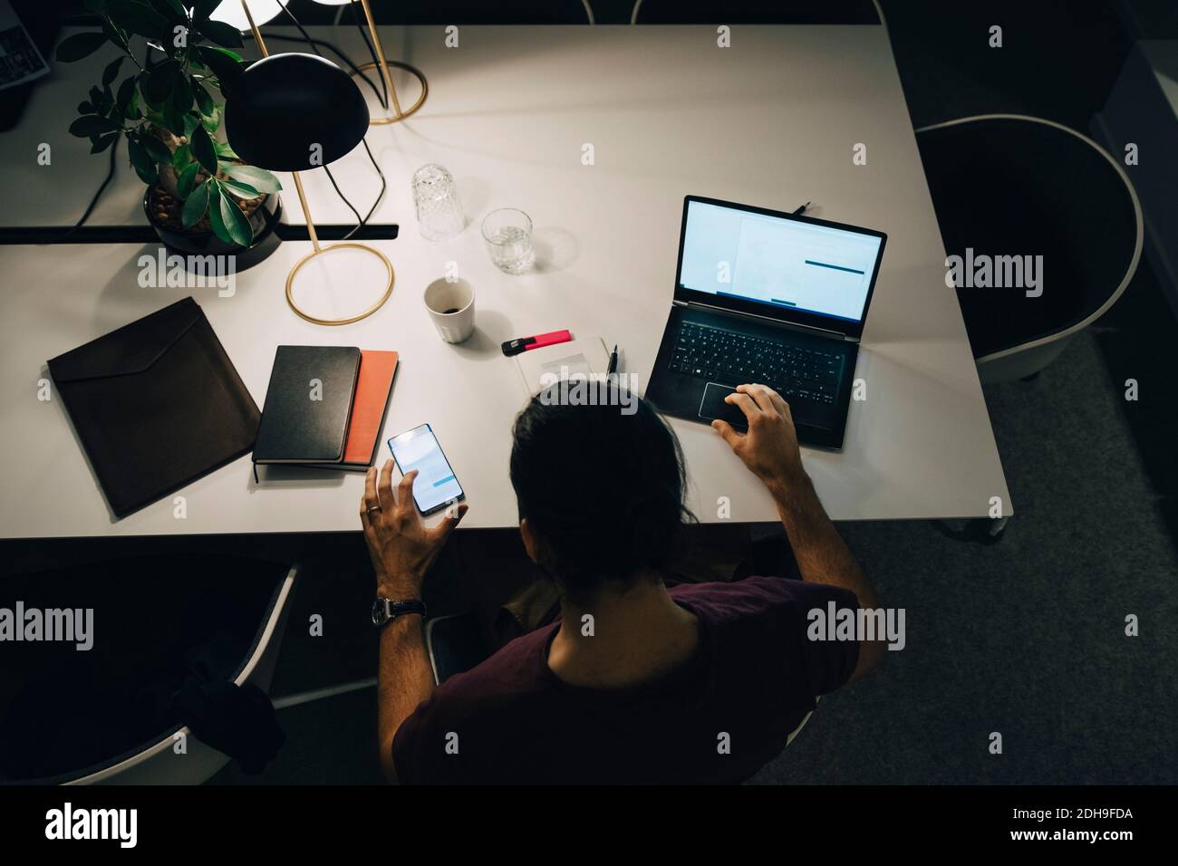 High angle rear view of businessman using mobile phone while working ...