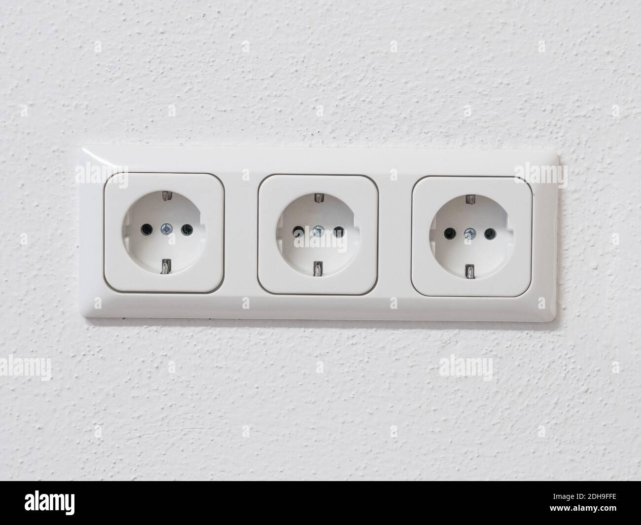 A closeup picture of electrical three white European sockets on the ...