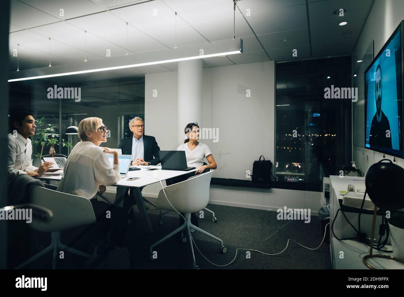 Colleagues looking at businessman during video conference meeting at ...