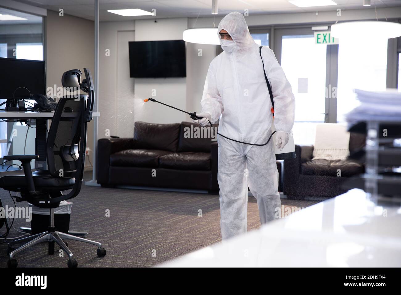 Health worker wearing protective clothes cleaning the office using ...