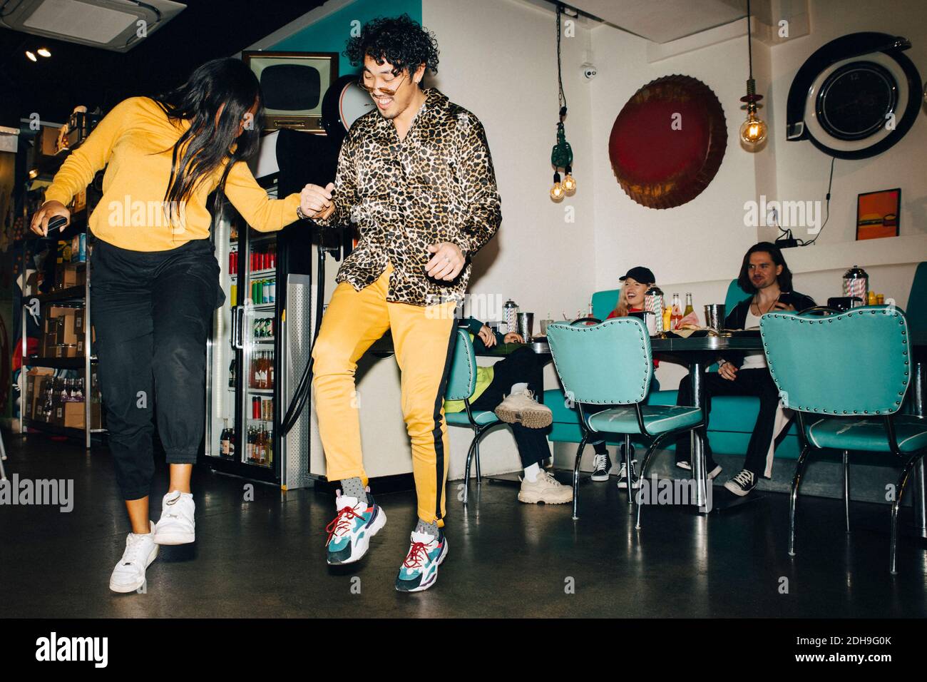 Smiling young man and woman dancing while friends watching in ...