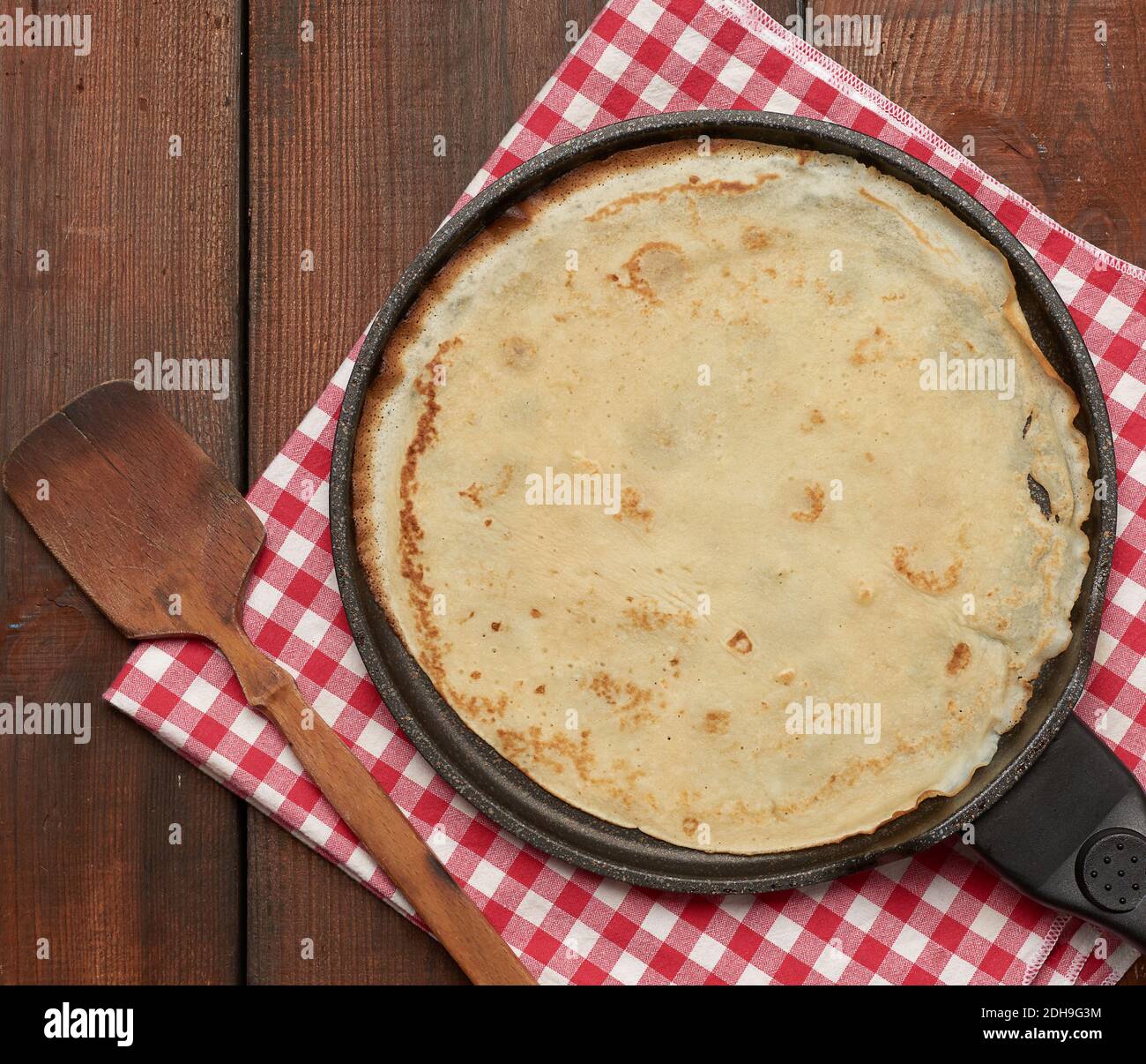 Baked round big pancake in a black frying pan Stock Photo - Alamy