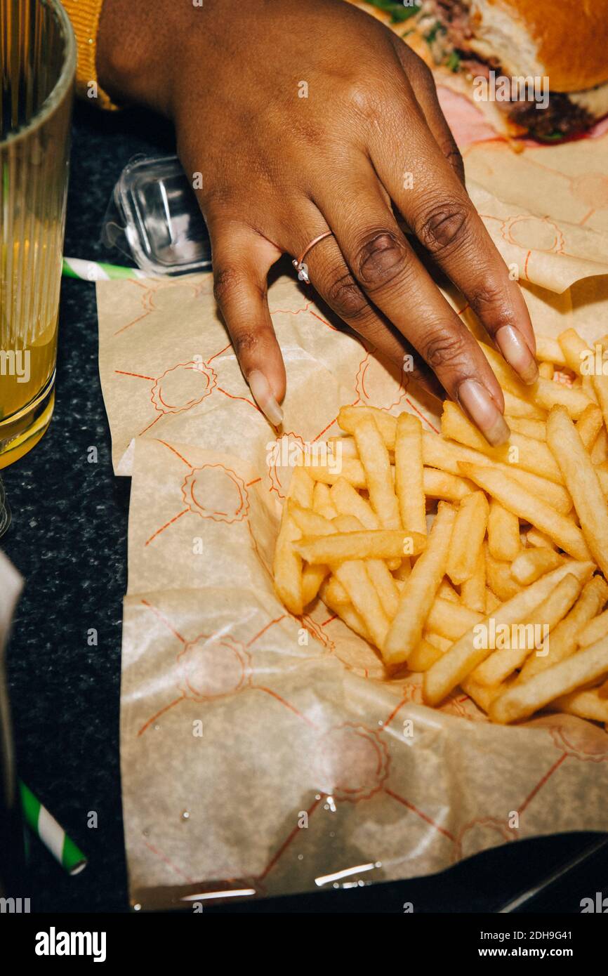 High angle view of woman's hand on french fries at table in cafe Stock ...