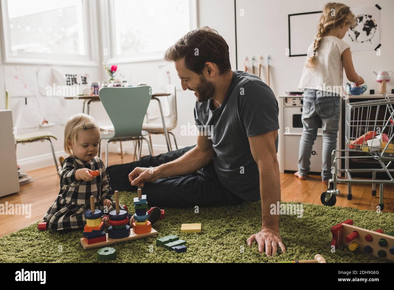 Father and daughters playing with toys in playroom at home Stock Photo ...
