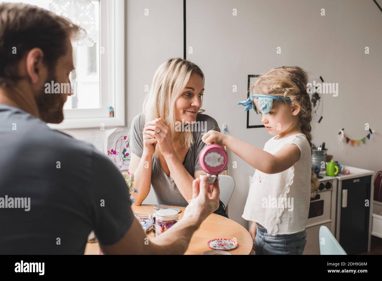 Parents and daughter having tea party in playroom Stock Photo - Alamy