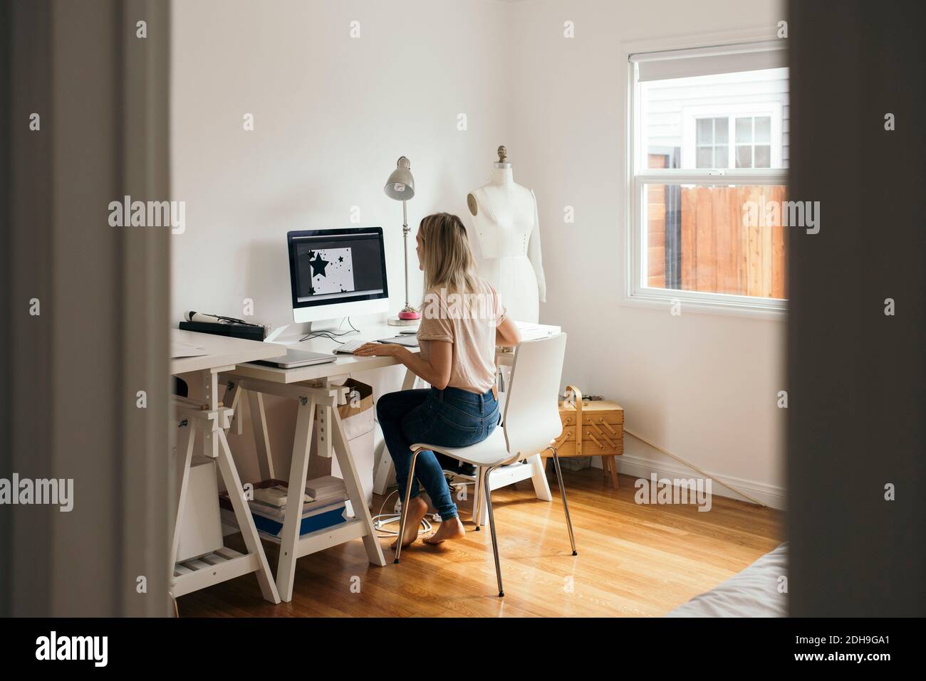 Full length rear view of graphic designer using computer at home Stock ...