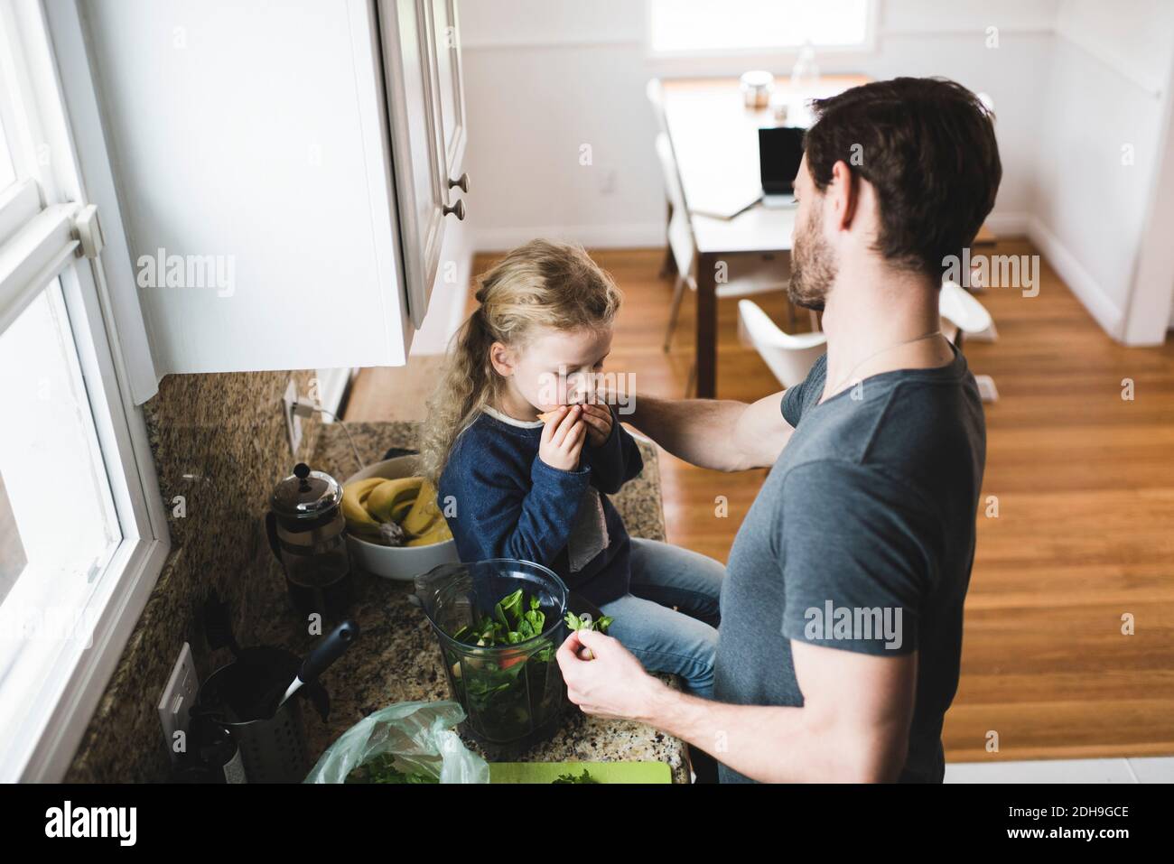 High angle view of father cooking food while daughter having fruit in ...