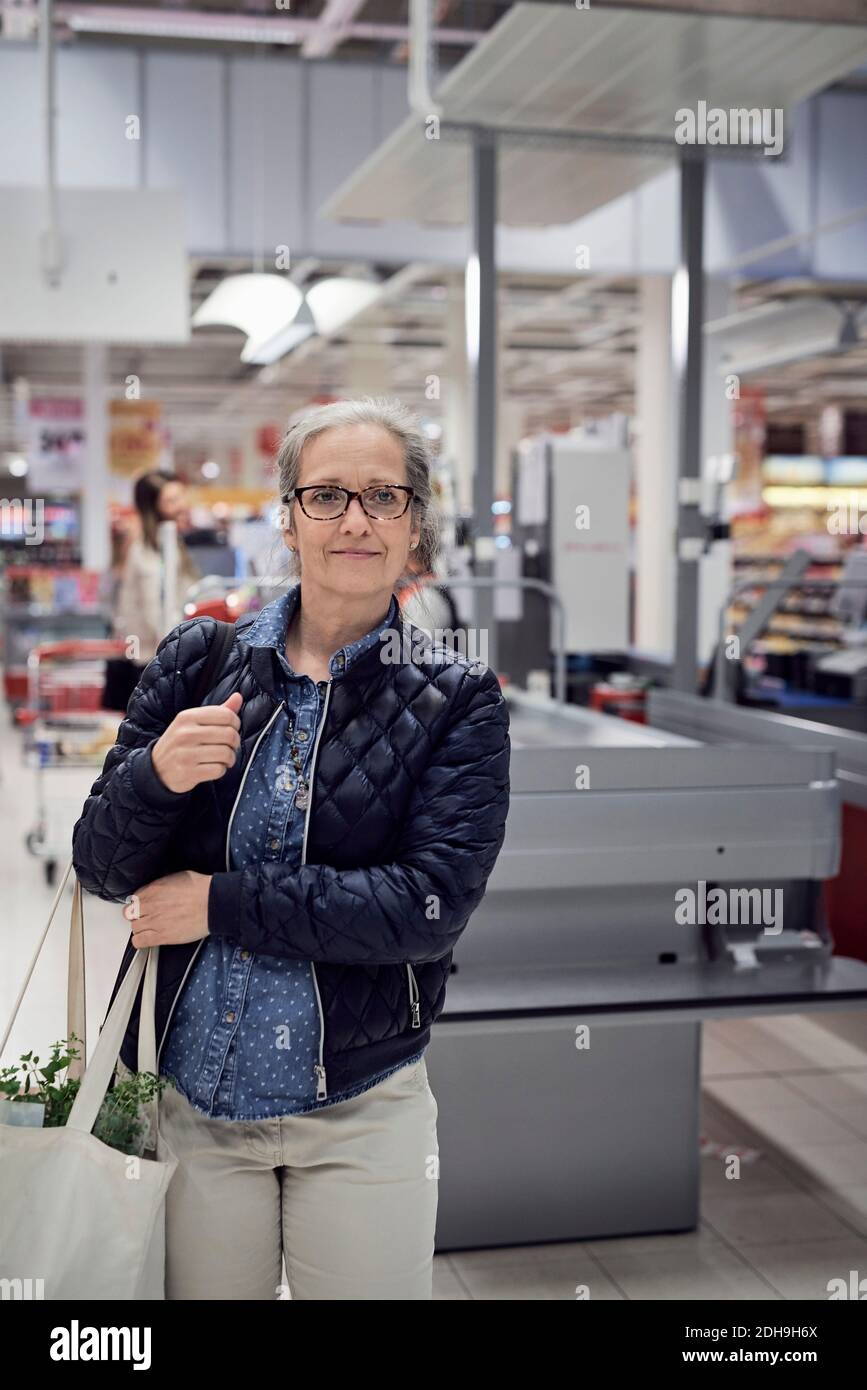 Smiling Mature Woman Carrying Shopping Bag While Looking Away Against
