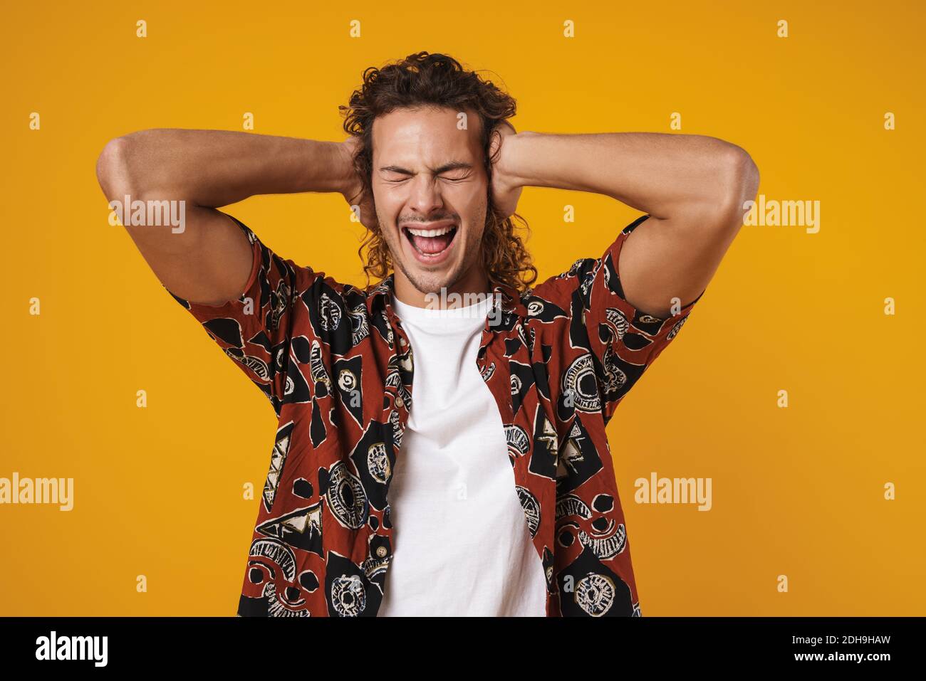 Photo of irritated caucasian guy screaming and covering his ears ...