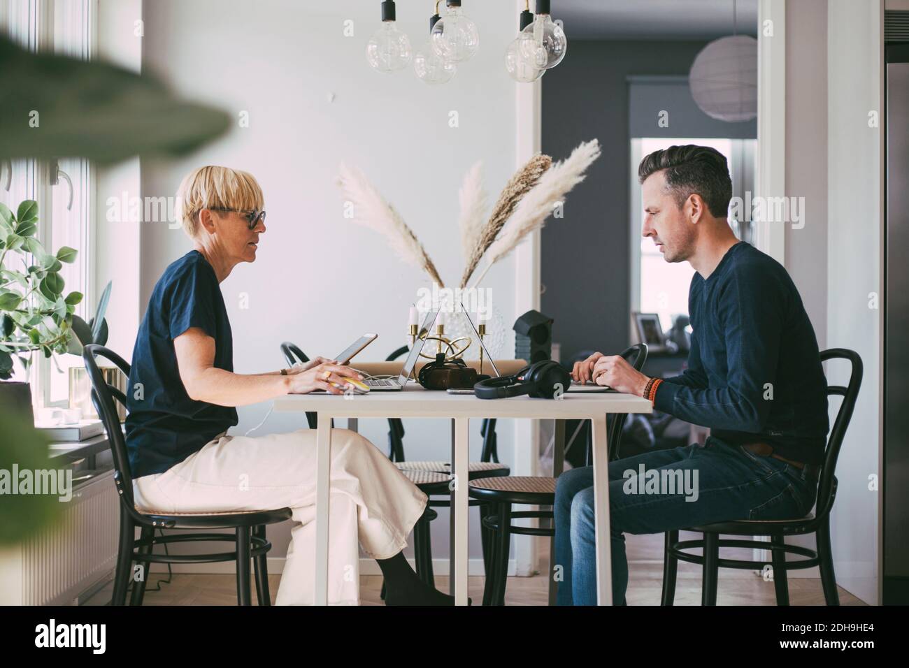 Profile of woman and man at table working from home Stock Photo - Alamy