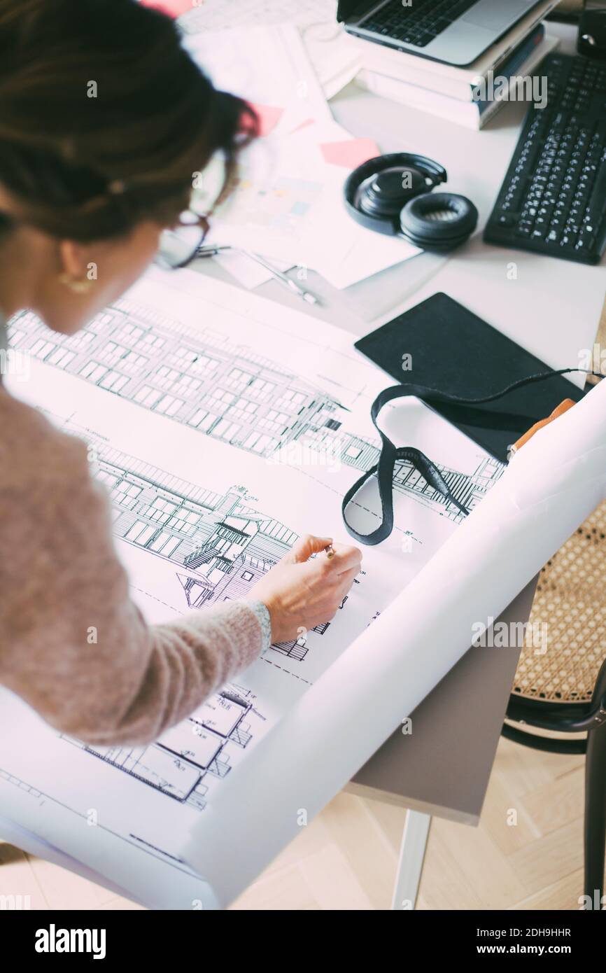 Architect looking at blueprint in office at home Stock Photo - Alamy