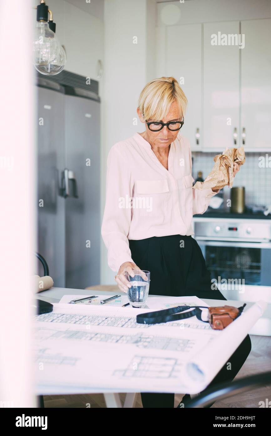 Architect having a standing lunch in kitchen working at home Stock ...