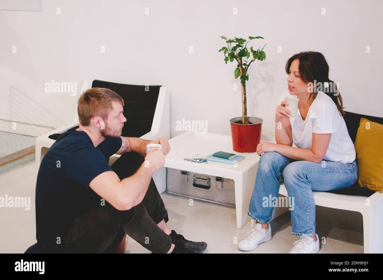 Creative business colleagues holding coffee cups while talking at ...