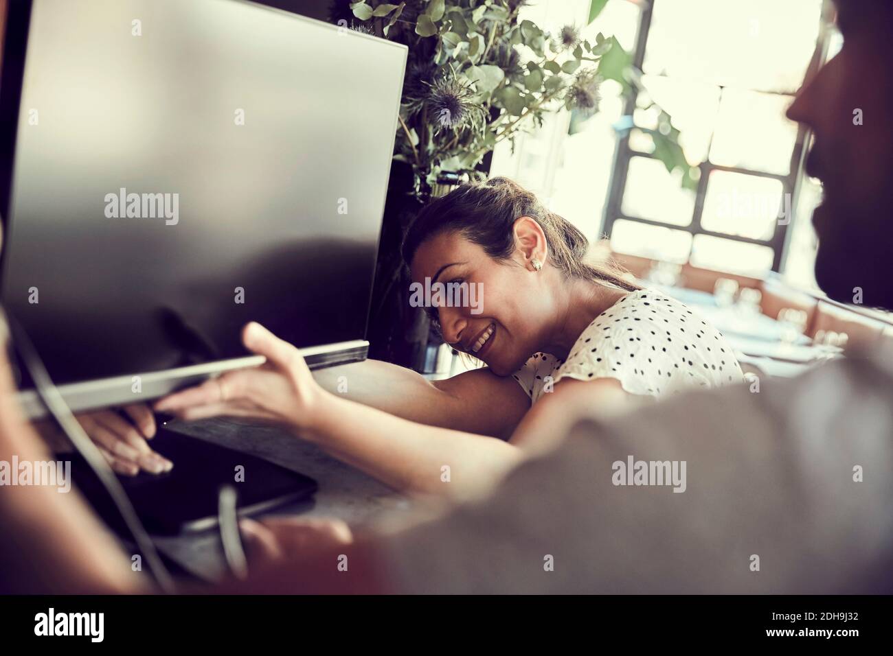 Smiling female with male owner adjusting cable of computer monitor in ...