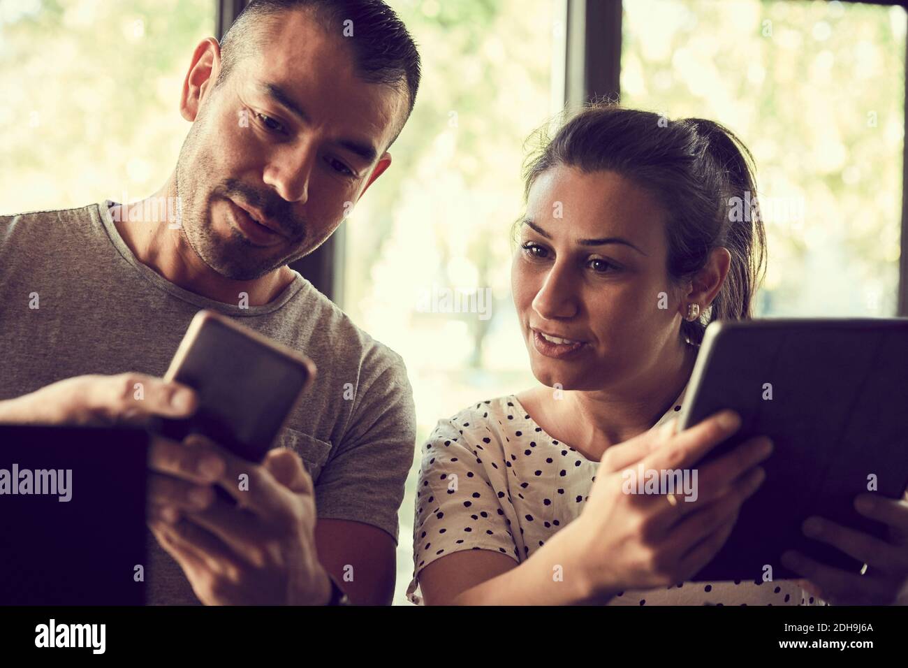 Male showing mobile phone to female partner in cafe Stock Photo - Alamy