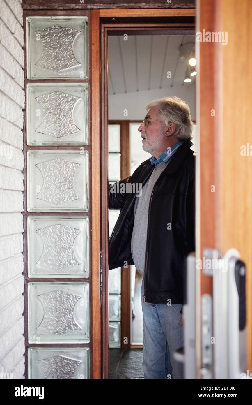 Side view of senior man standing in room seen through ajar Stock Photo ...