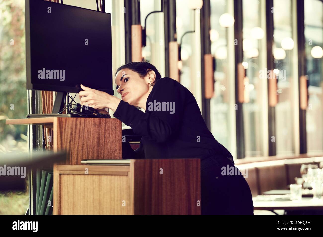 Female owner adjusting computer monitor in cafe Stock Photo - Alamy