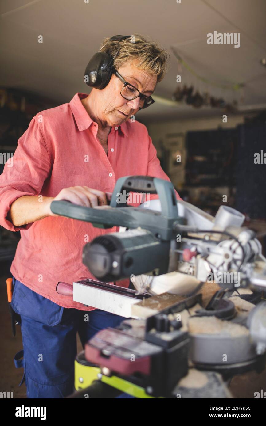 Senior woman using circular saw at workshop Stock Photo - Alamy