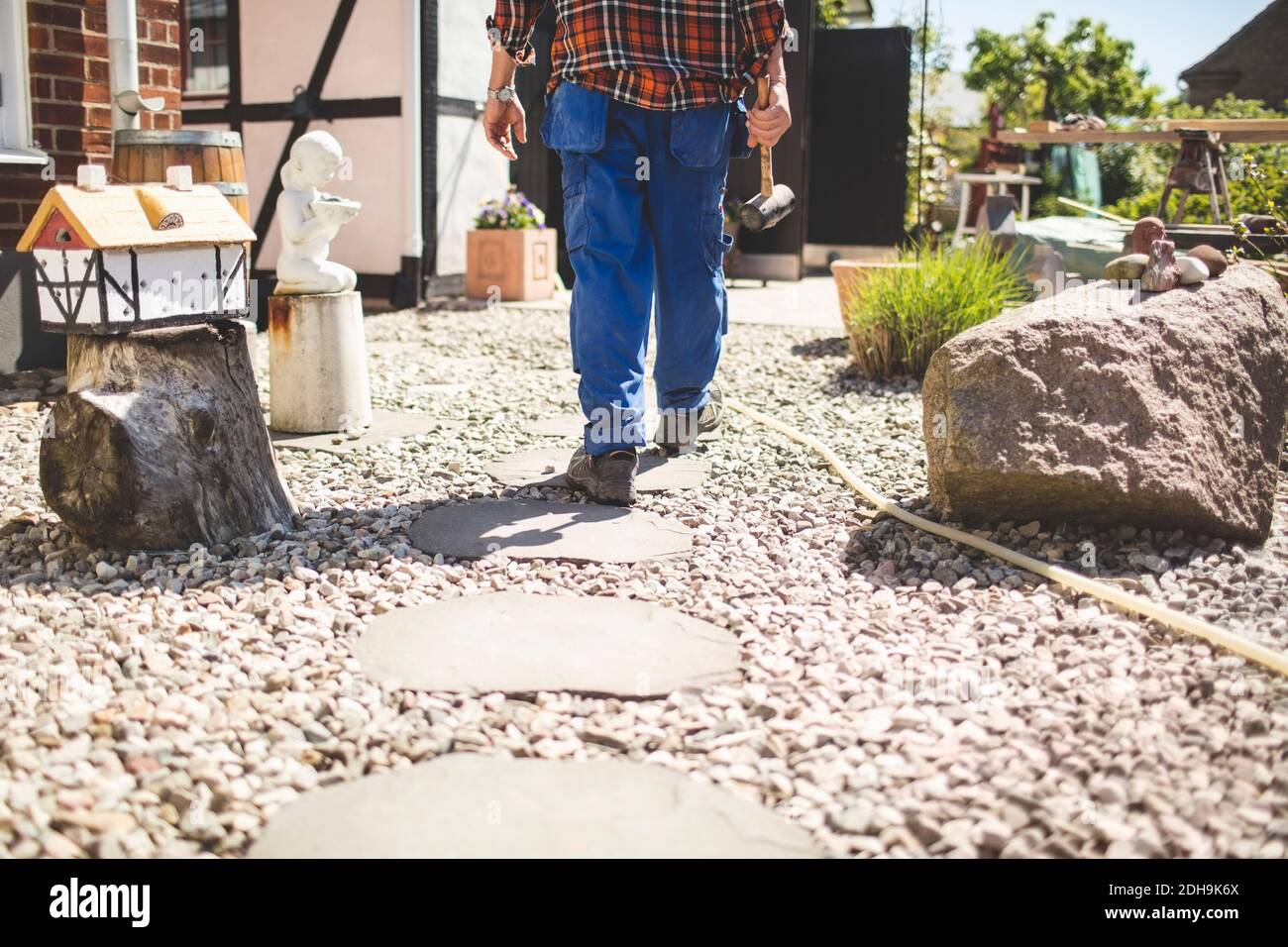 Low section of senior man holding hammer while walking at yard Stock ...