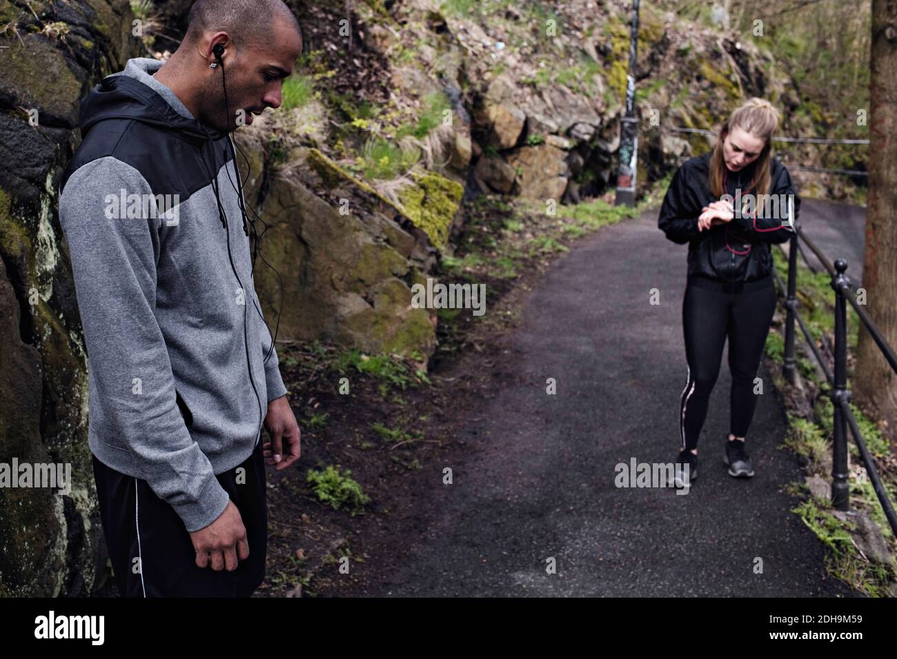 Side view of tired male athlete standing on road with woman in ...