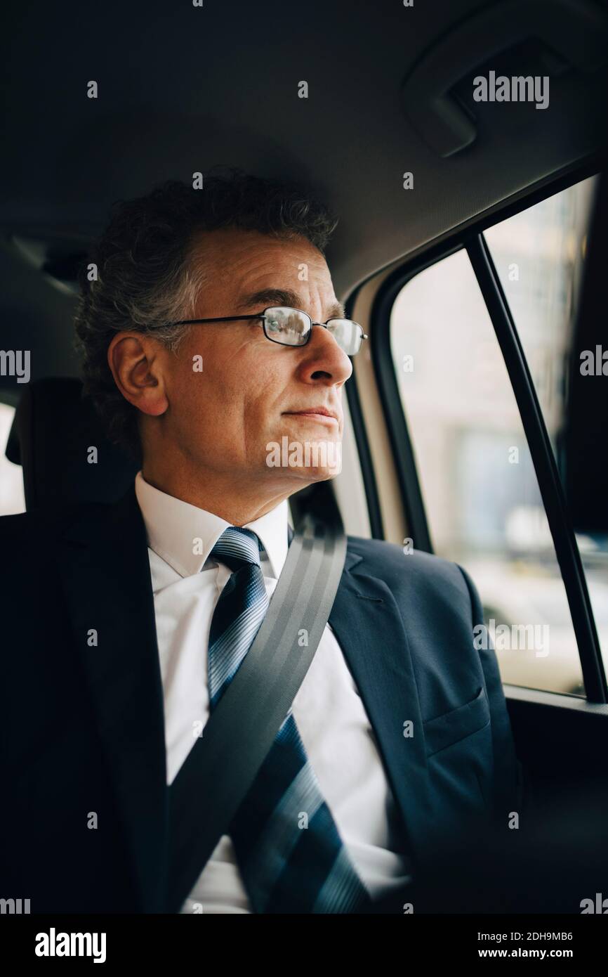 Entrepreneur looking through window while sitting in taxi Stock Photo ...