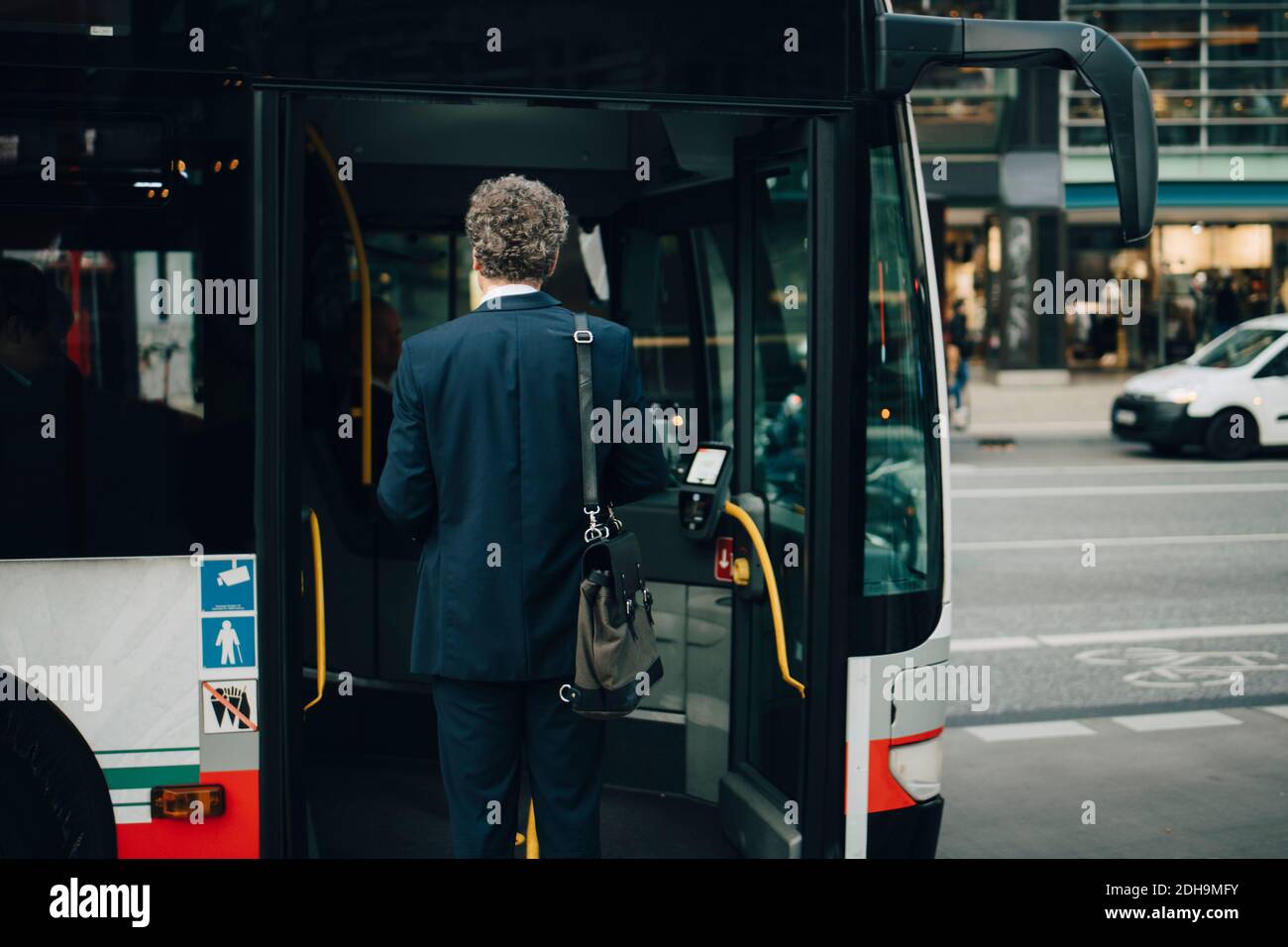 Rear view of male entrepreneur entering bus during business trip in ...