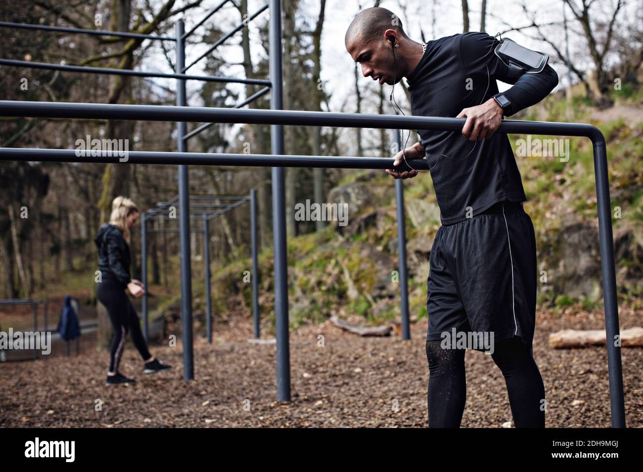 Male and female athletes standing at parallel bars in forest Stock ...