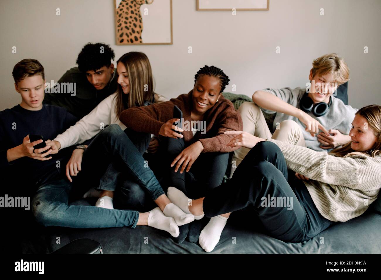 Smiling teenage friends using social media on mobile phones while ...