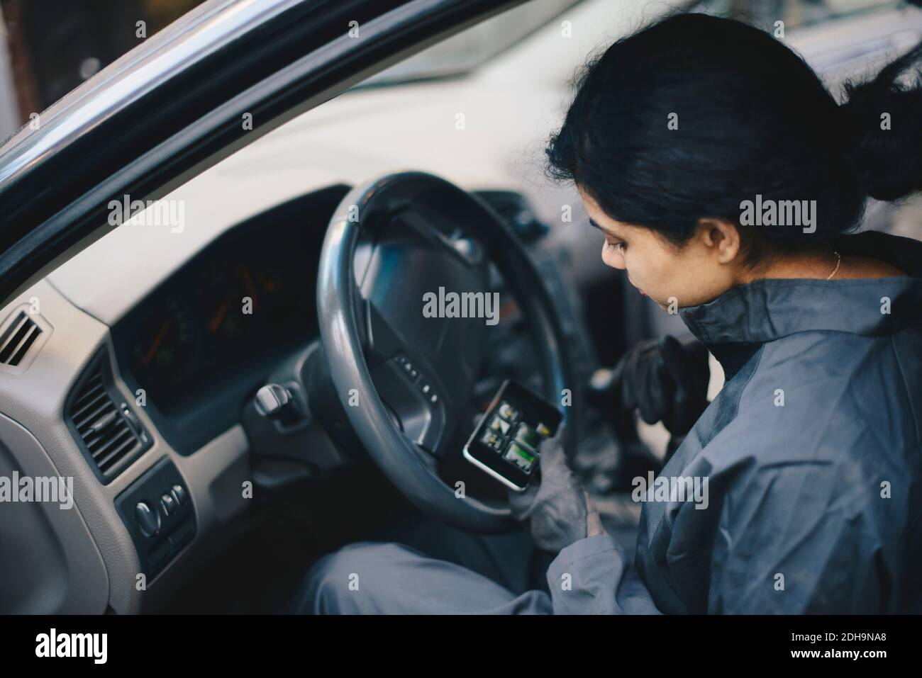 Female mechanic using mobile phone while sitting in car Stock Photo - Alamy