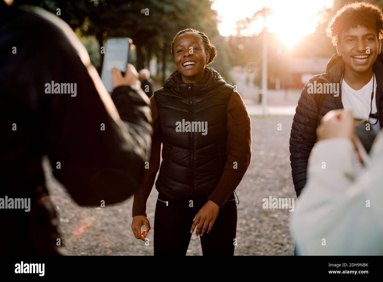 Friends filming smiling teenage girl and boy dancing on street in city ...