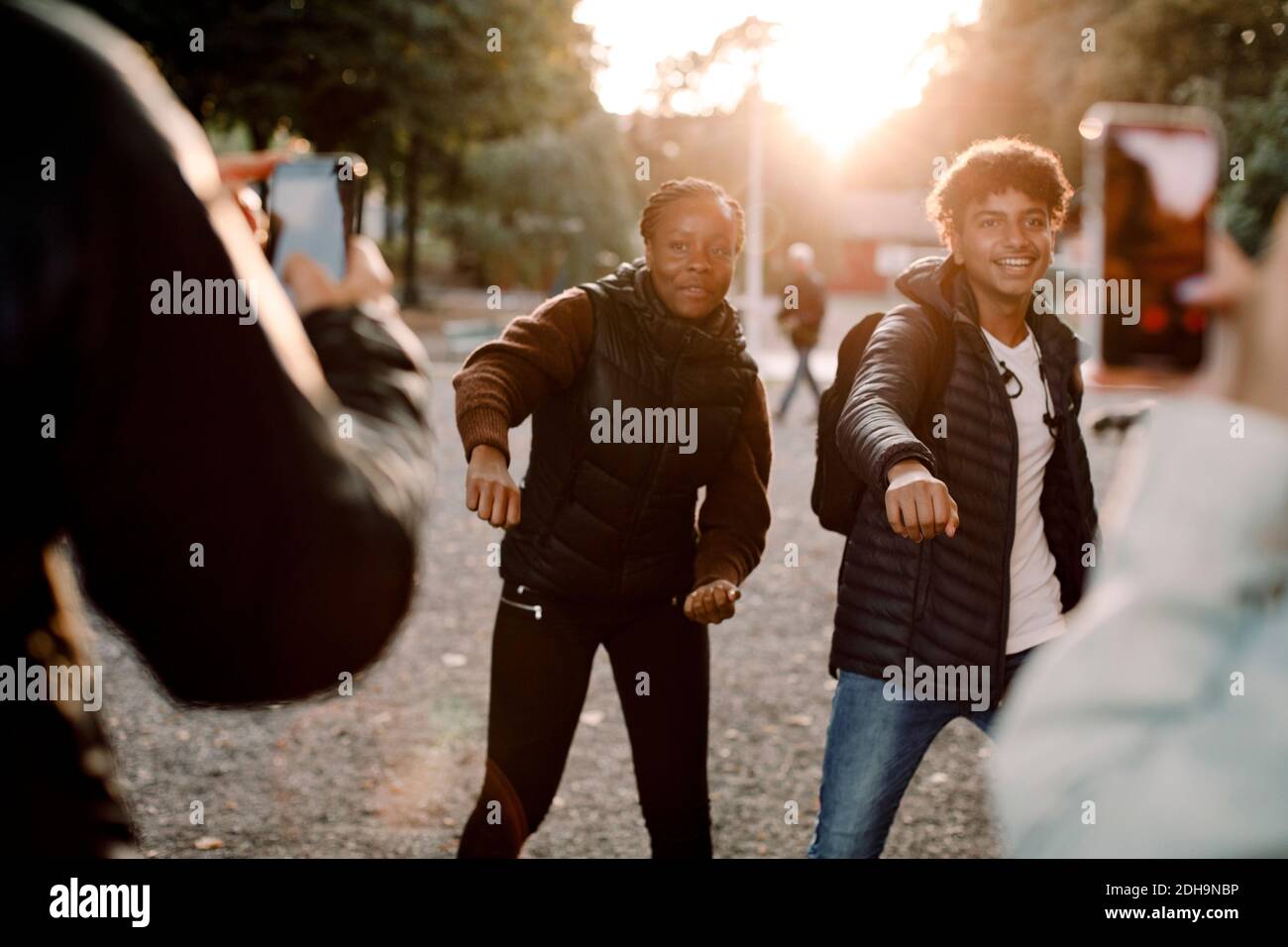 Friends filming teenage girl and boy dancing on street in city Stock ...