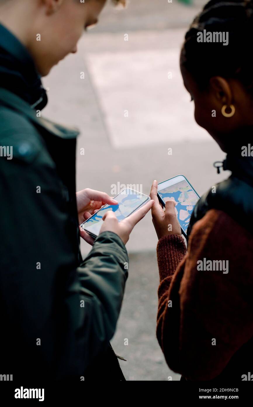 Teenage girl and boy searching for friends through app on smart phones ...