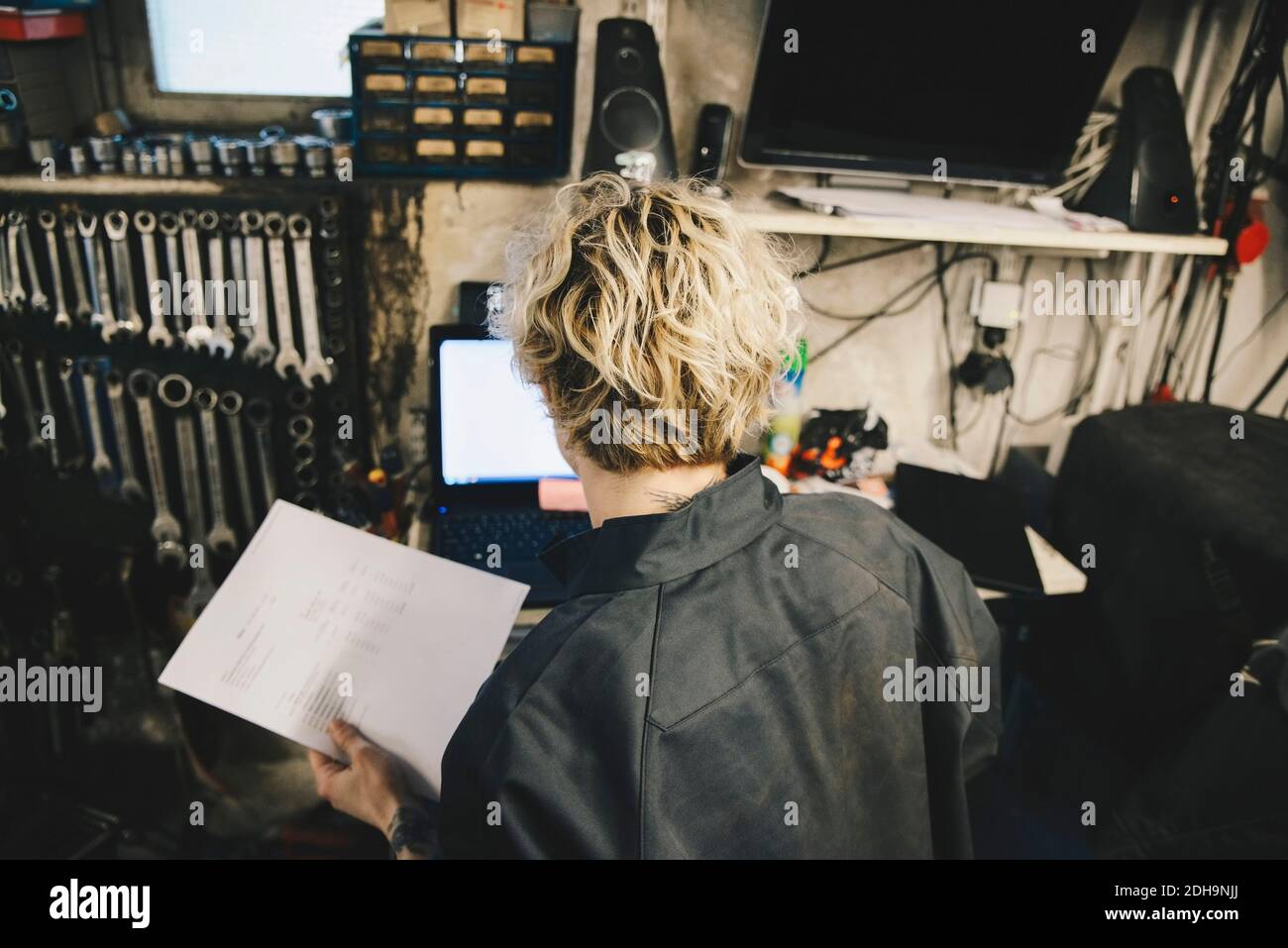 Rear view of female customer holding bill at auto repair shop Stock ...