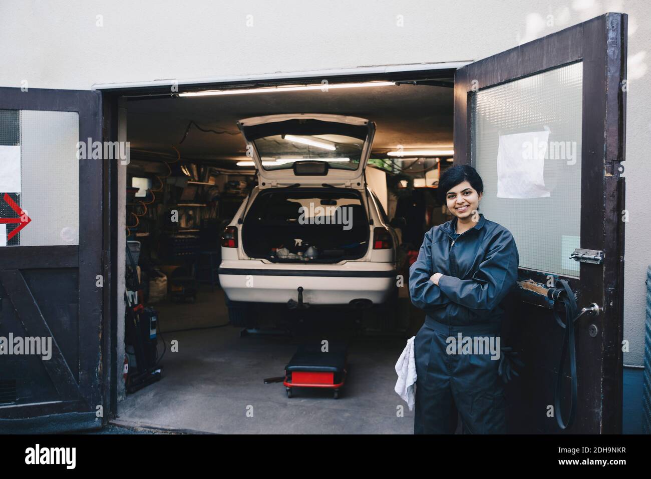 Portrait of confident female mechanic standing with arms crossed at ...