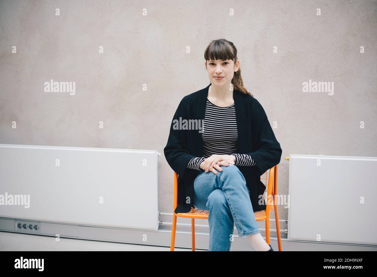 Portrait of confident female computer programmer sitting on chair ...