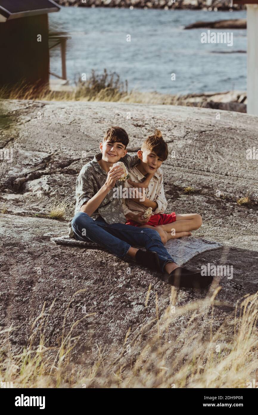 Portrait of male siblings sitting on blanket over archipelago during ...