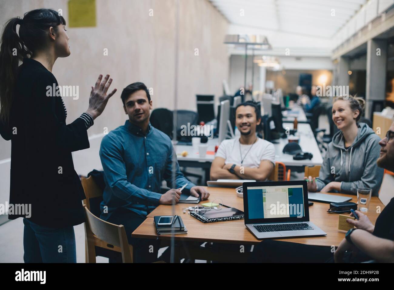 Female computer programmer giving presentation to colleagues in office ...