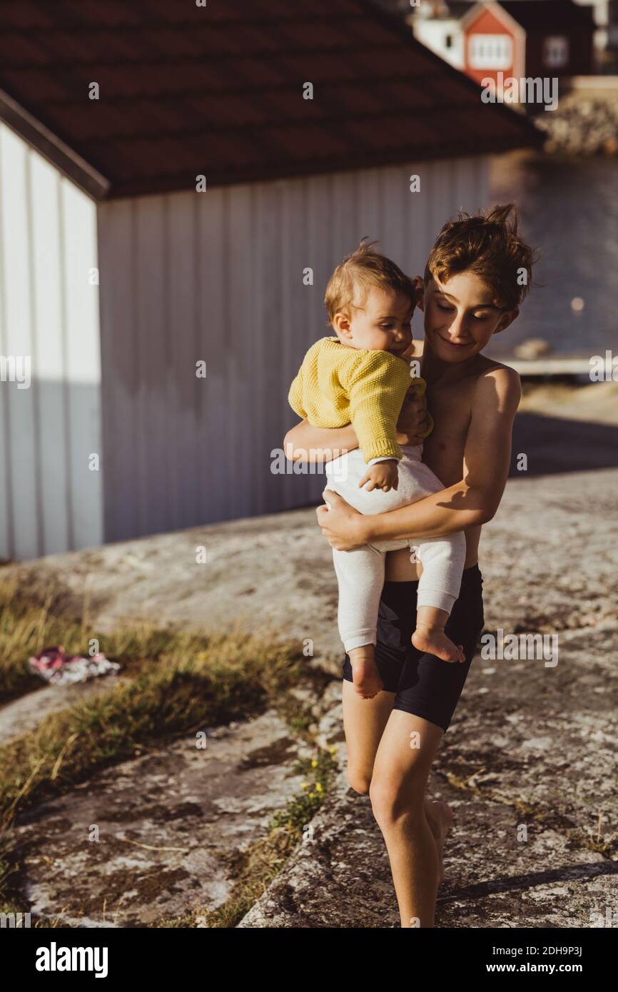 Smiling brother carrying baby sister while walking on archipelago Stock ...
