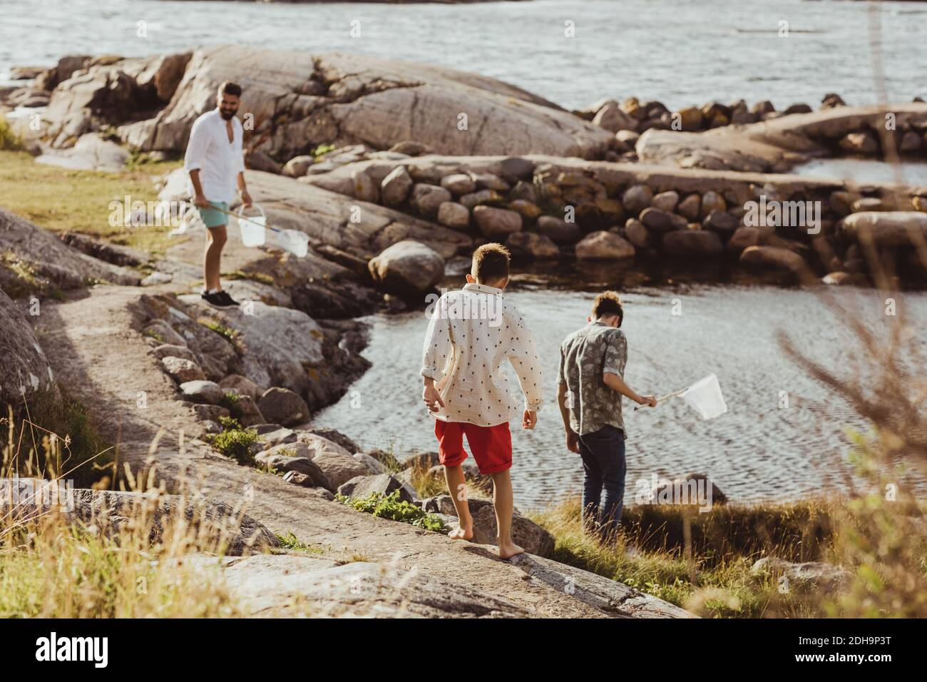 Rear view of boy with sibling while father standing over rock during ...