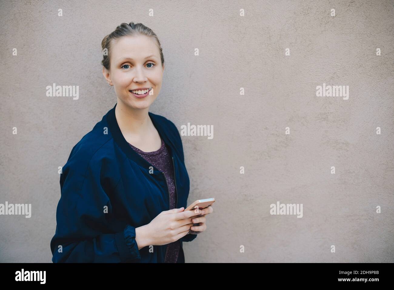 Portrait of happy female computer programmer holding smart phone while ...