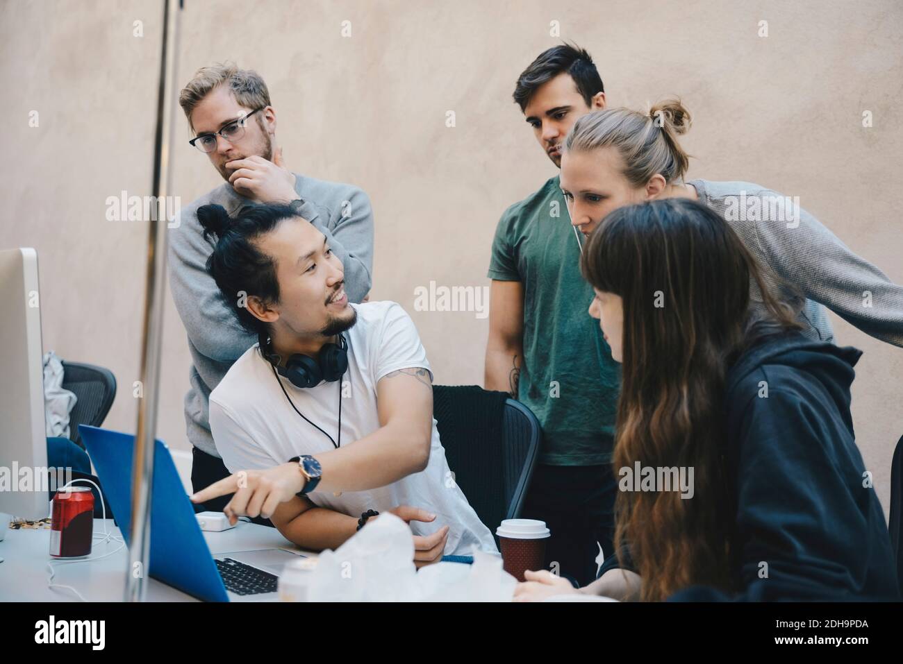Male computer programmer showing laptop to colleagues in office Stock ...
