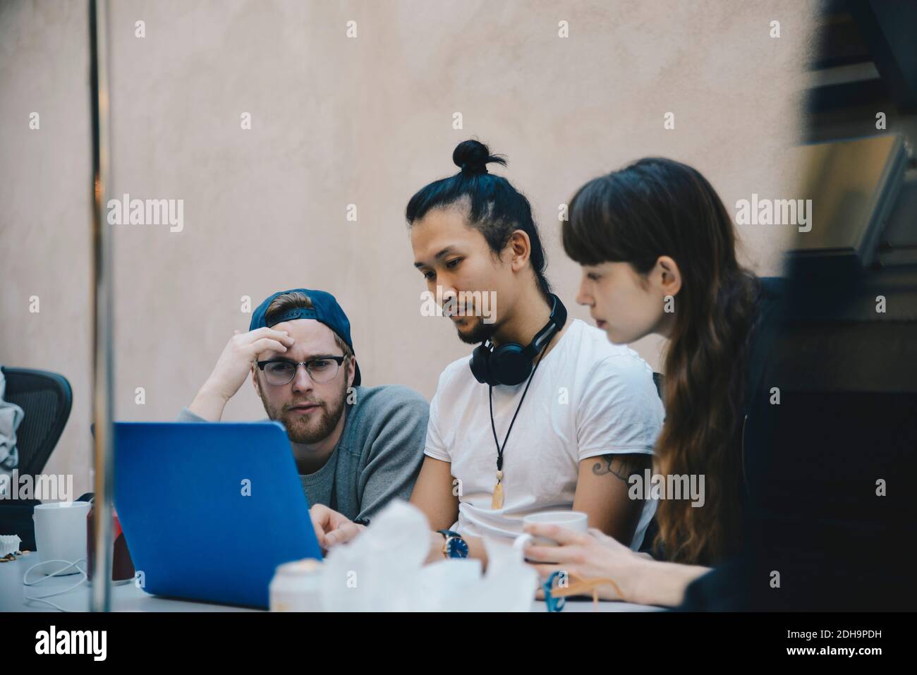 Computer programmers using laptop at desk in office Stock Photo - Alamy