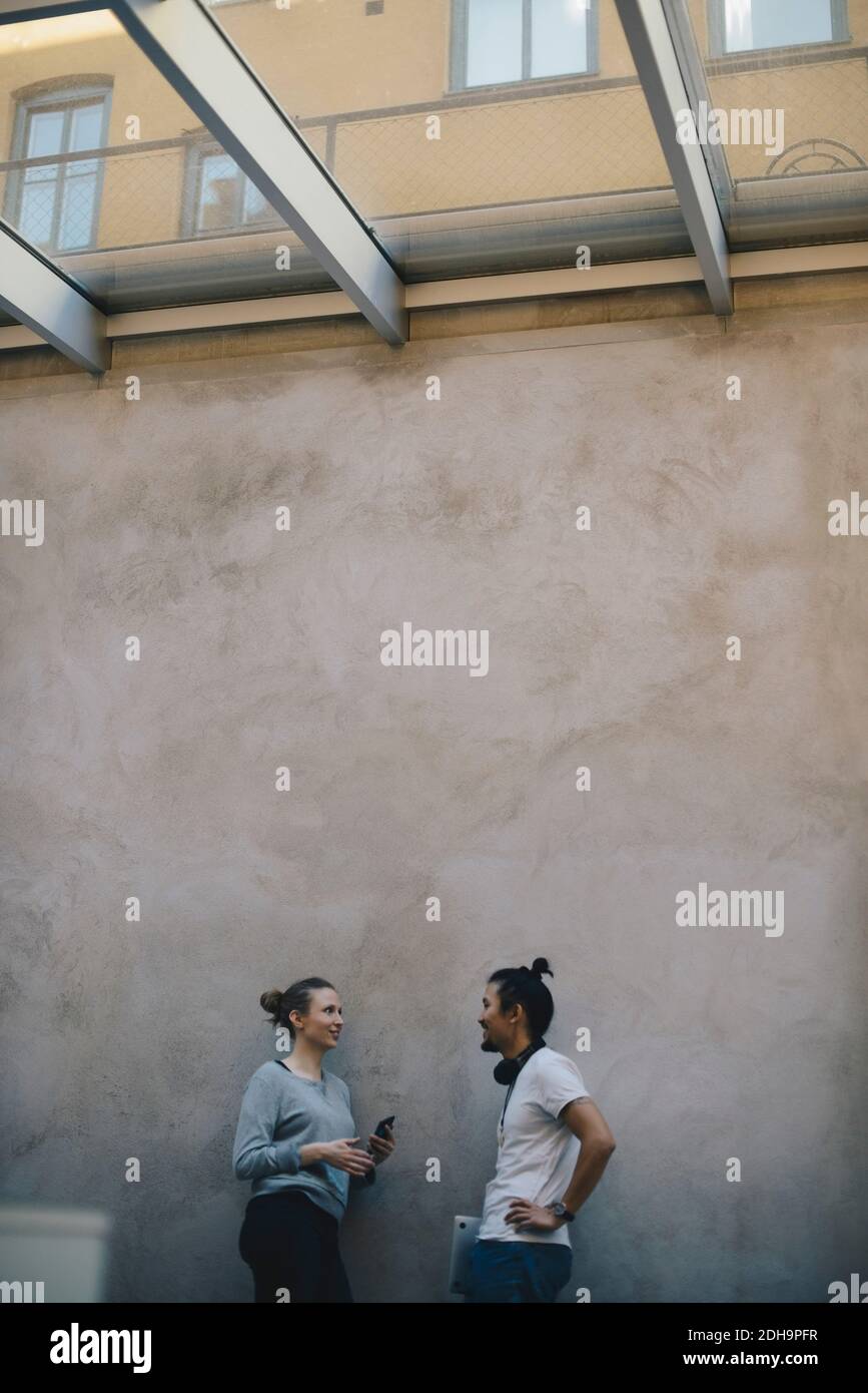 Computer programmers discussing against wall in office Stock Photo - Alamy