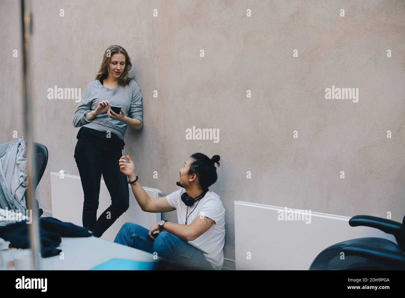 Male computer programmer talking to female colleague holding smart ...