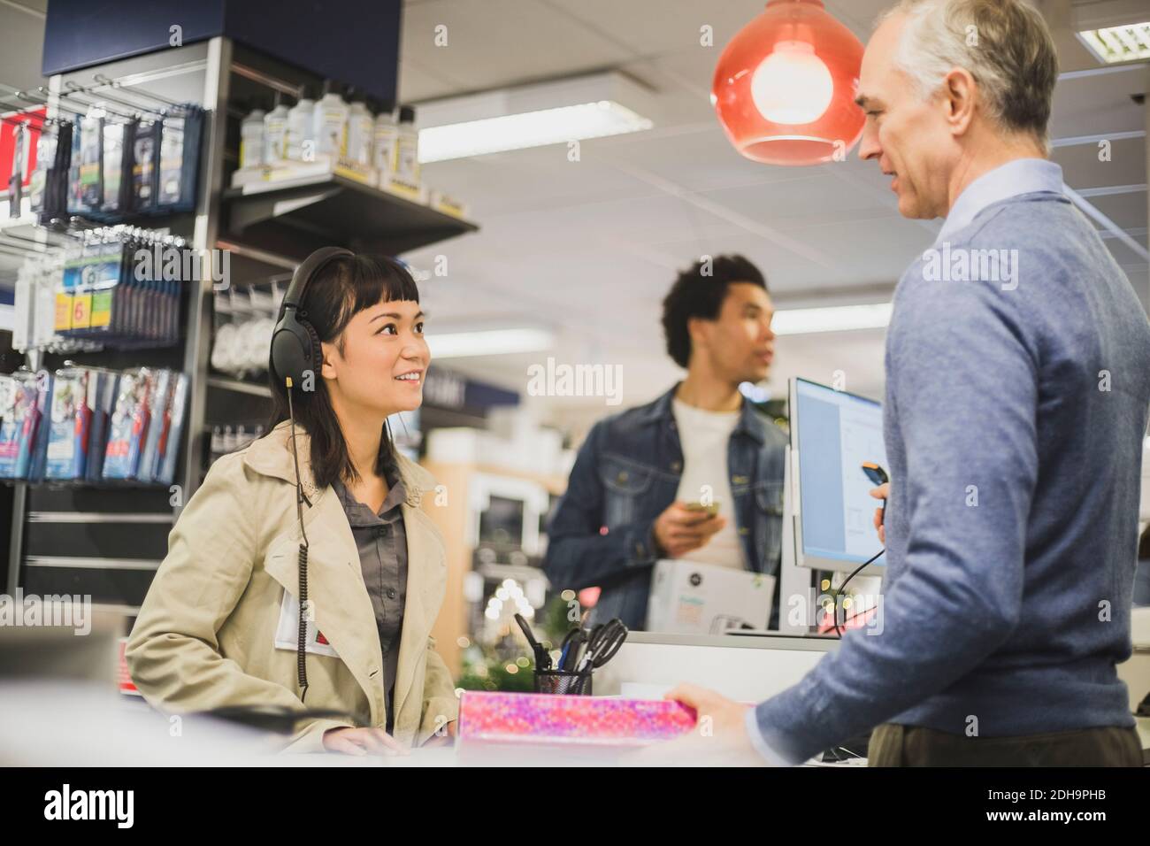 Smiling female customer talking to mature owner in electronics store ...
