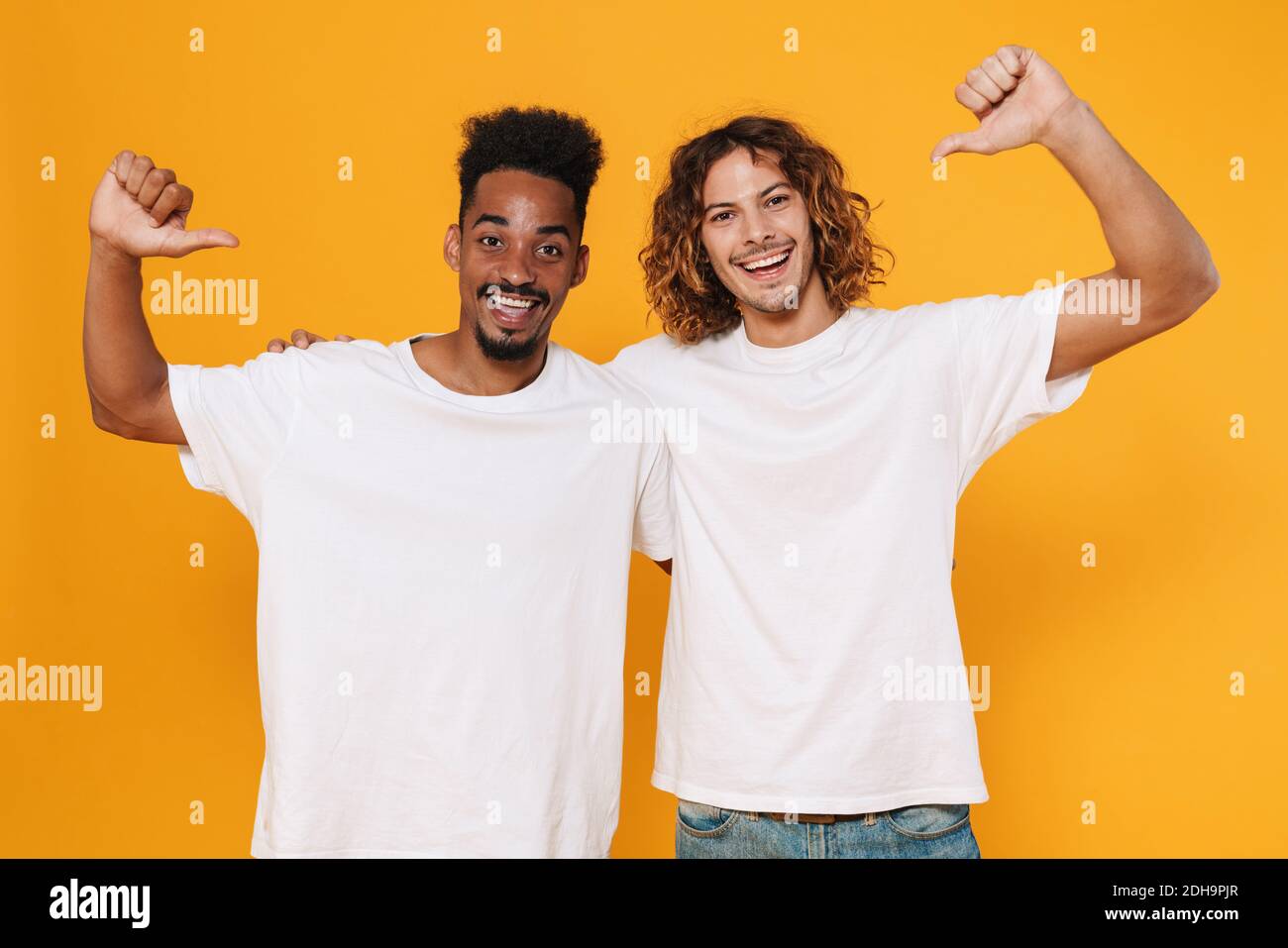 Happy multicultural two guys pointing fingers at themselves and hugging ...