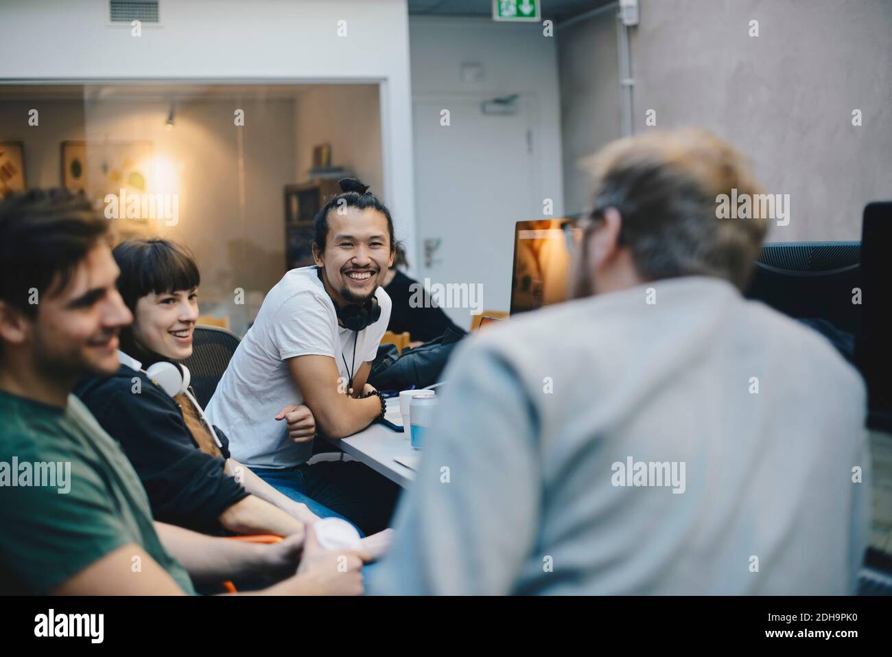 Happy computer programmers talking at desk in office Stock Photo - Alamy