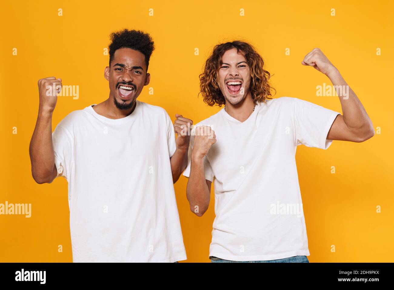 Excited multicultural two guys screaming and making winner gesture ...