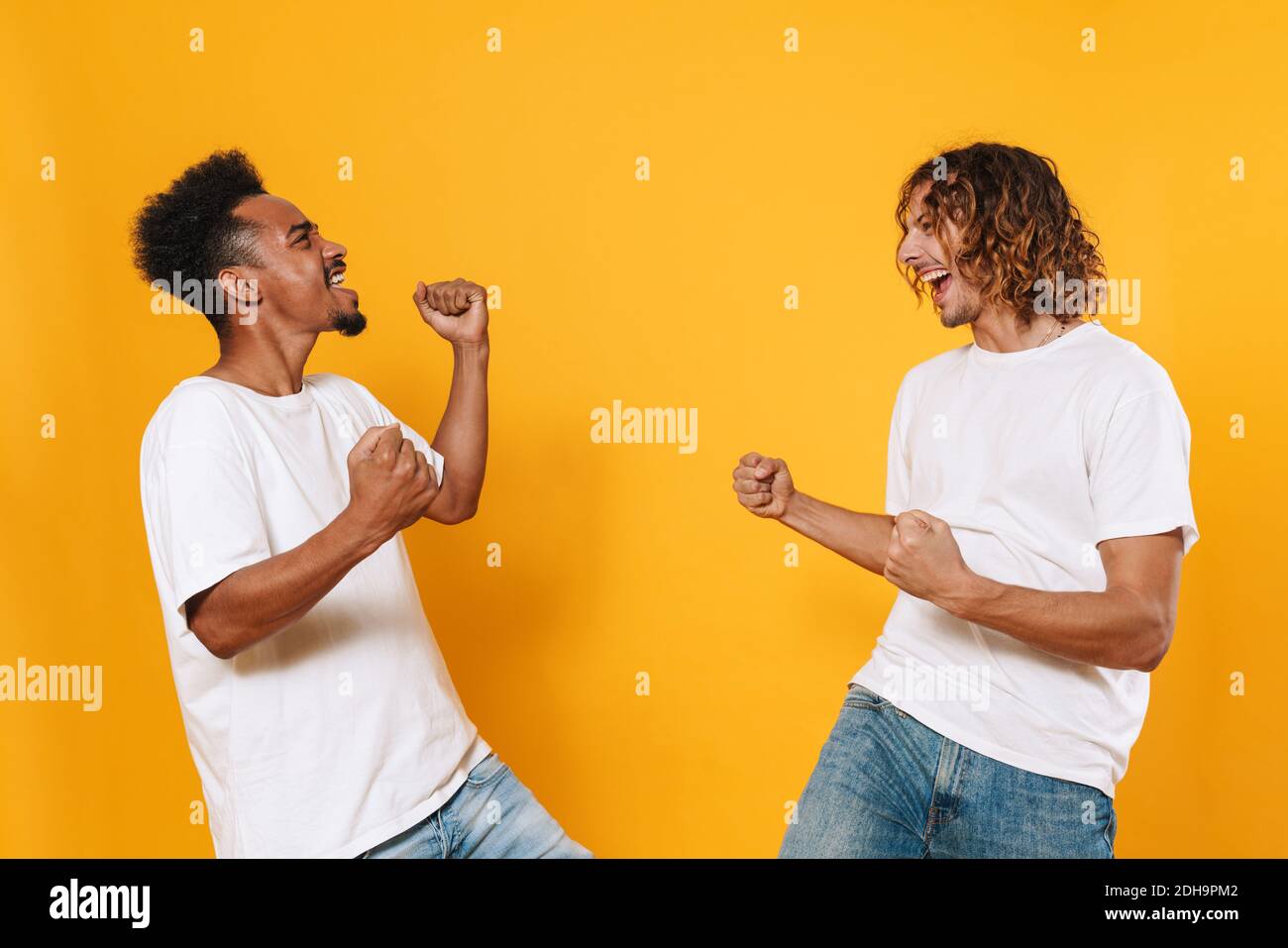 Excited multicultural two guys screaming and making winner gesture ...