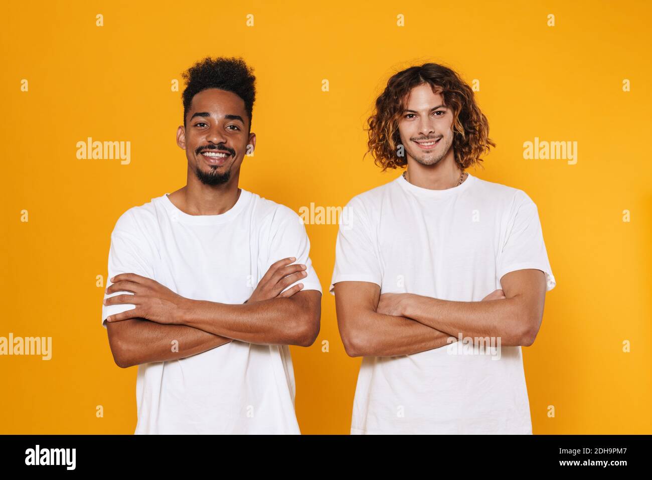 Happy multicultural two guys posing with arms crossed isolated over ...